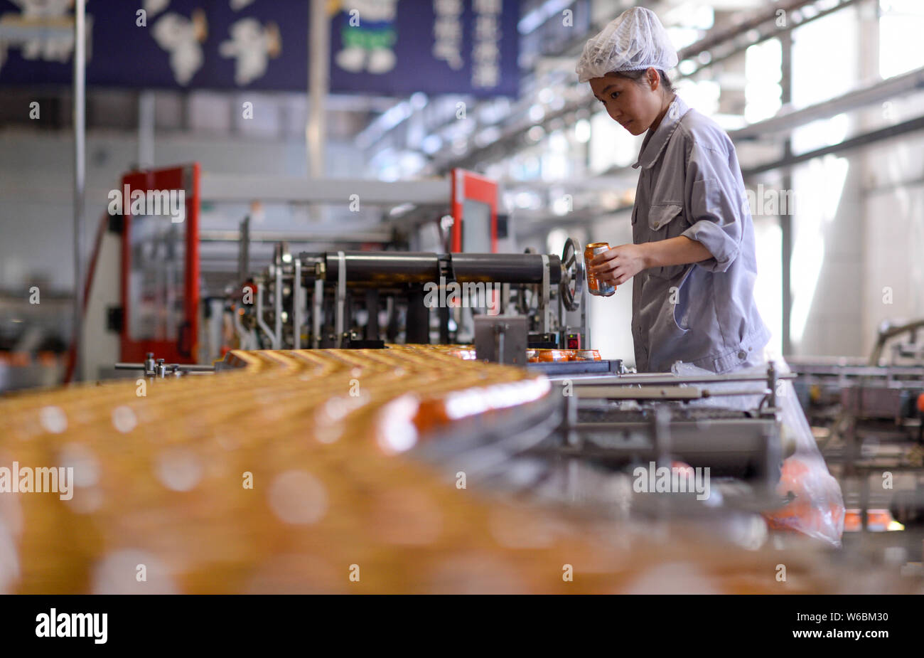 A Chinese worker checks the production of cans of orange soda on the ...
