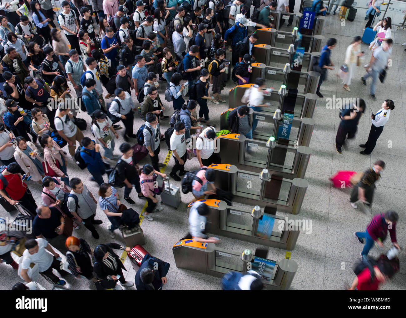 Passengers queue up to have their train tickets scanned for check-in ...