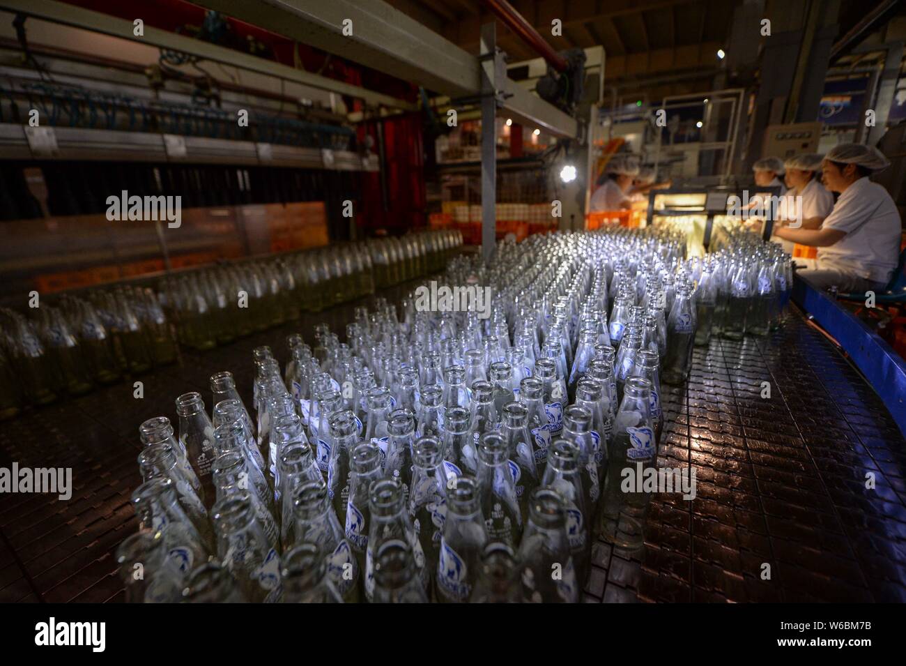 A Chinese worker checks bottles to be filled with orange soda on the ...