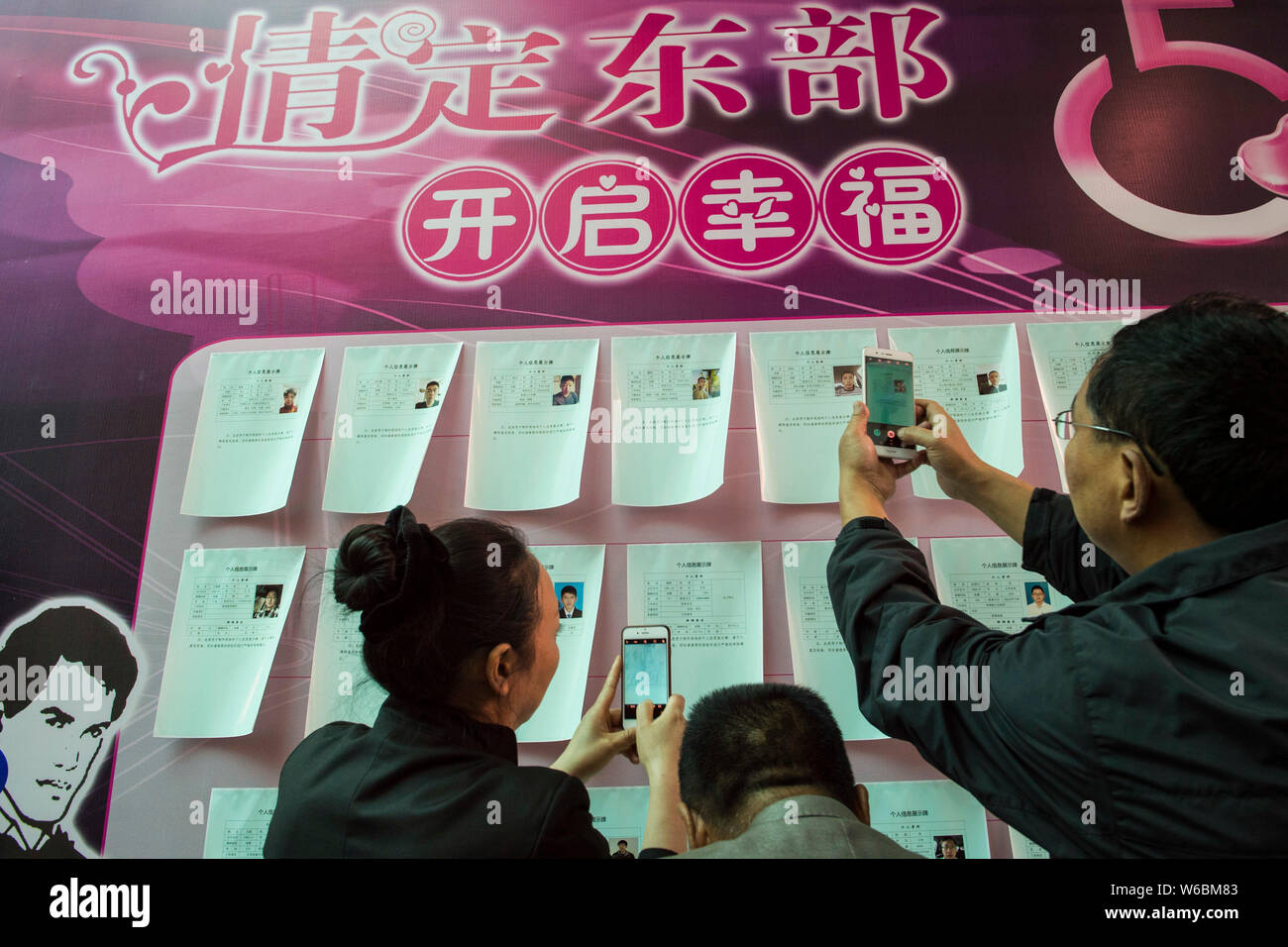 --FILE--Single people watch and take photos of posters showing personal ...