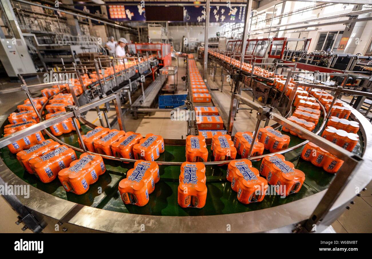 Cans of orange soda are being produced on the assembly line at the ...