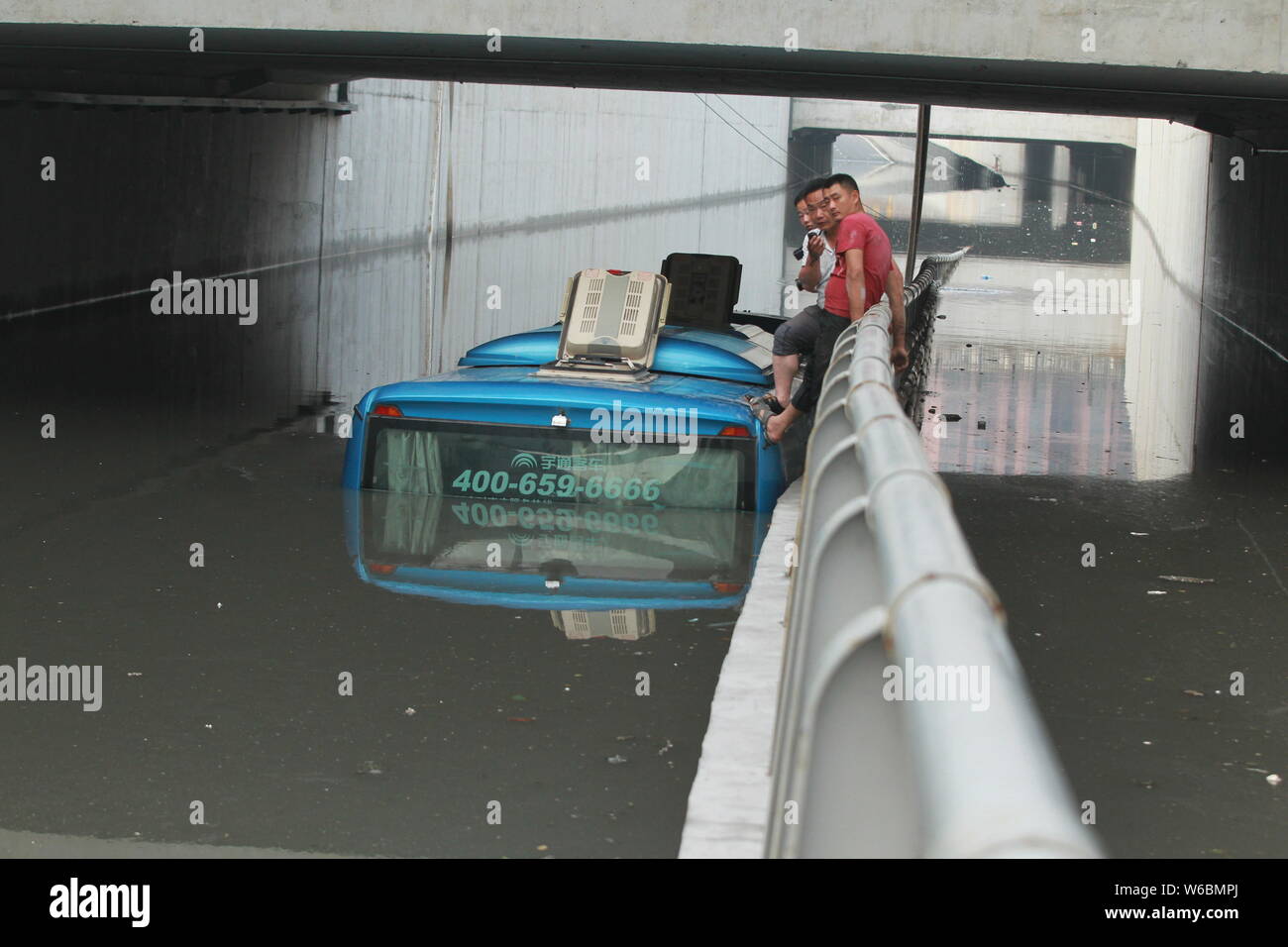 View of a submerged bus stuck under a flooded bridge caused by heavy ...