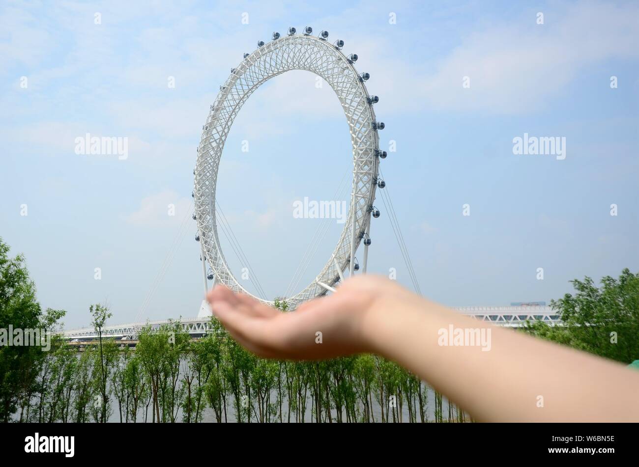 A visitor poses with Bailang River Bridge Ferris Wheel, the world's ...
