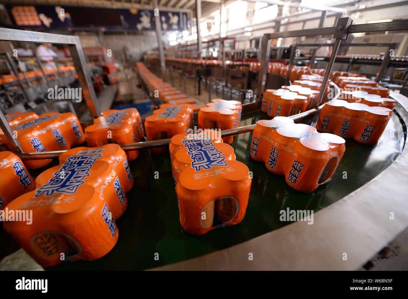 Cans of orange soda are being produced on the assembly line at the ...