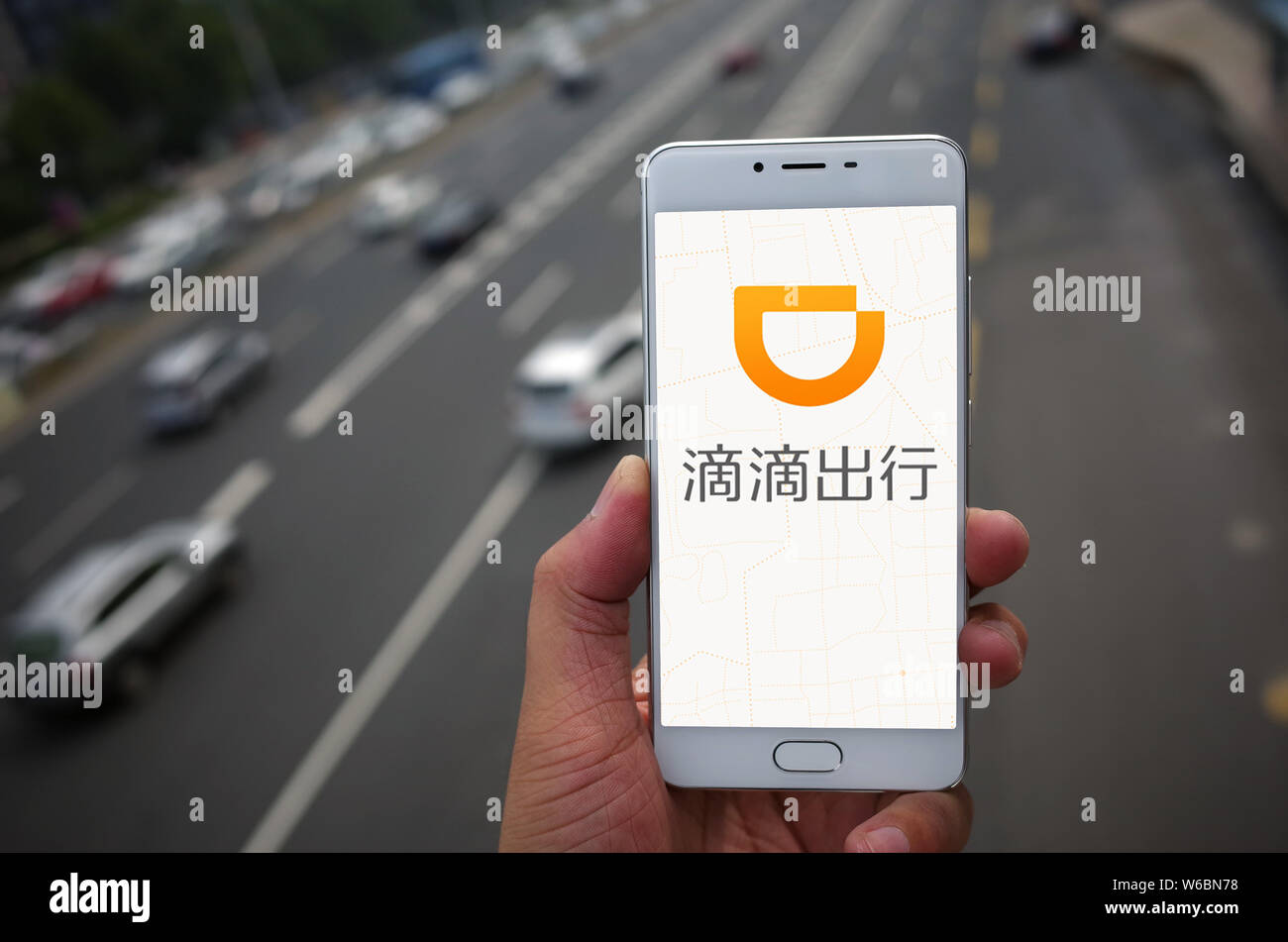 --FILE--A Chinese mobile user looks a logo of taxi-hailing and car ...