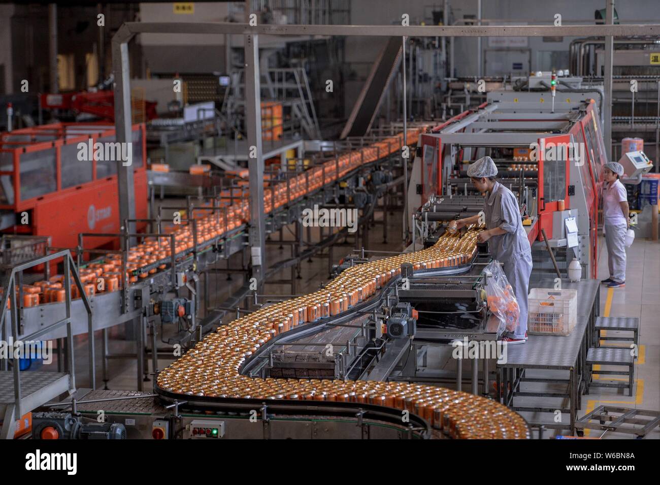 A Chinese worker checks the production of cans of orange soda on the ...