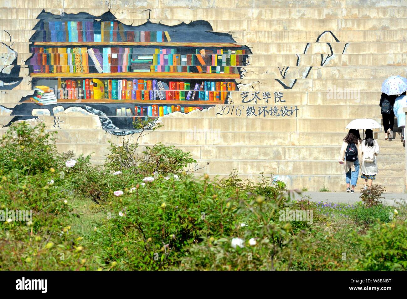 Students walk on a staircase with a 3D painting of a library at Lanzhou ...