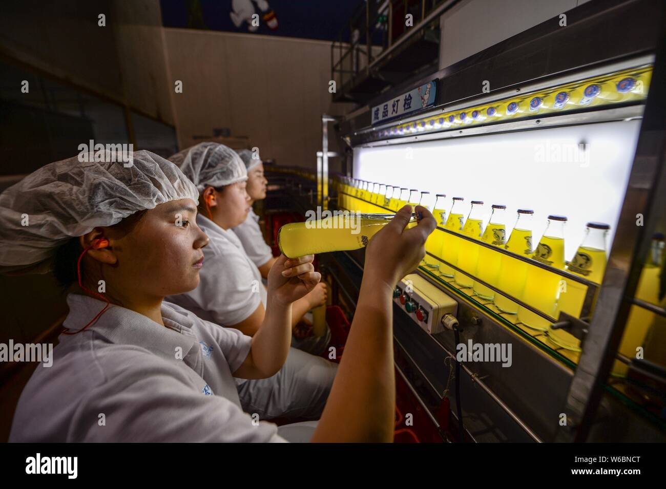 Chinese workers check the production of bottles of orange soda on the ...