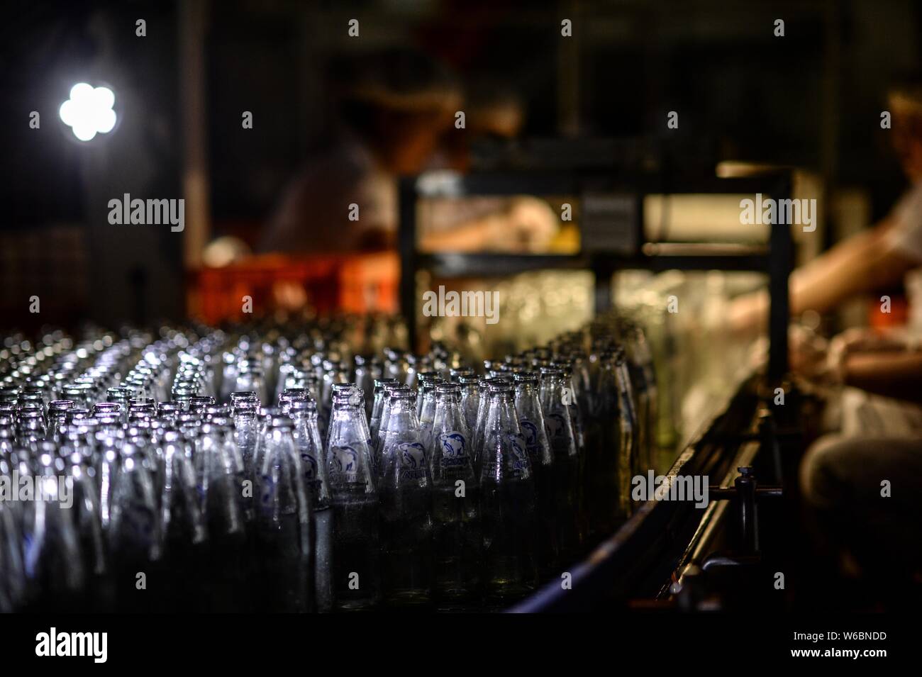 A Chinese worker checks bottles to be filled with orange soda on the ...
