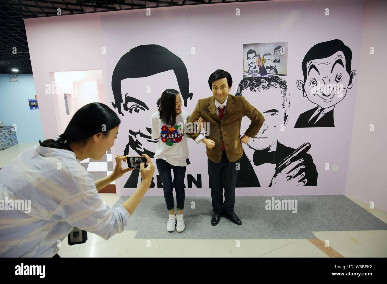A visitor poses for photos with a wax figure of English actor Rowan ...