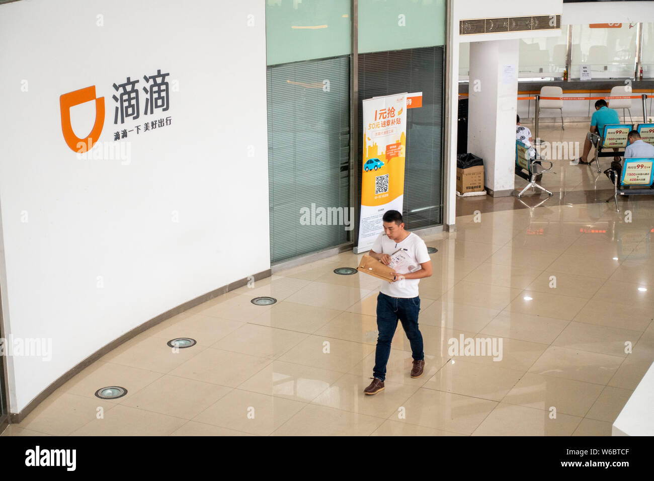 A pedestrian walks past a Didi Club of the taxi-hailing and car-service ...