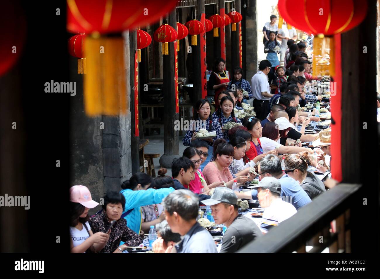 Tourists and local residents eat along tables at along-table banquet ...