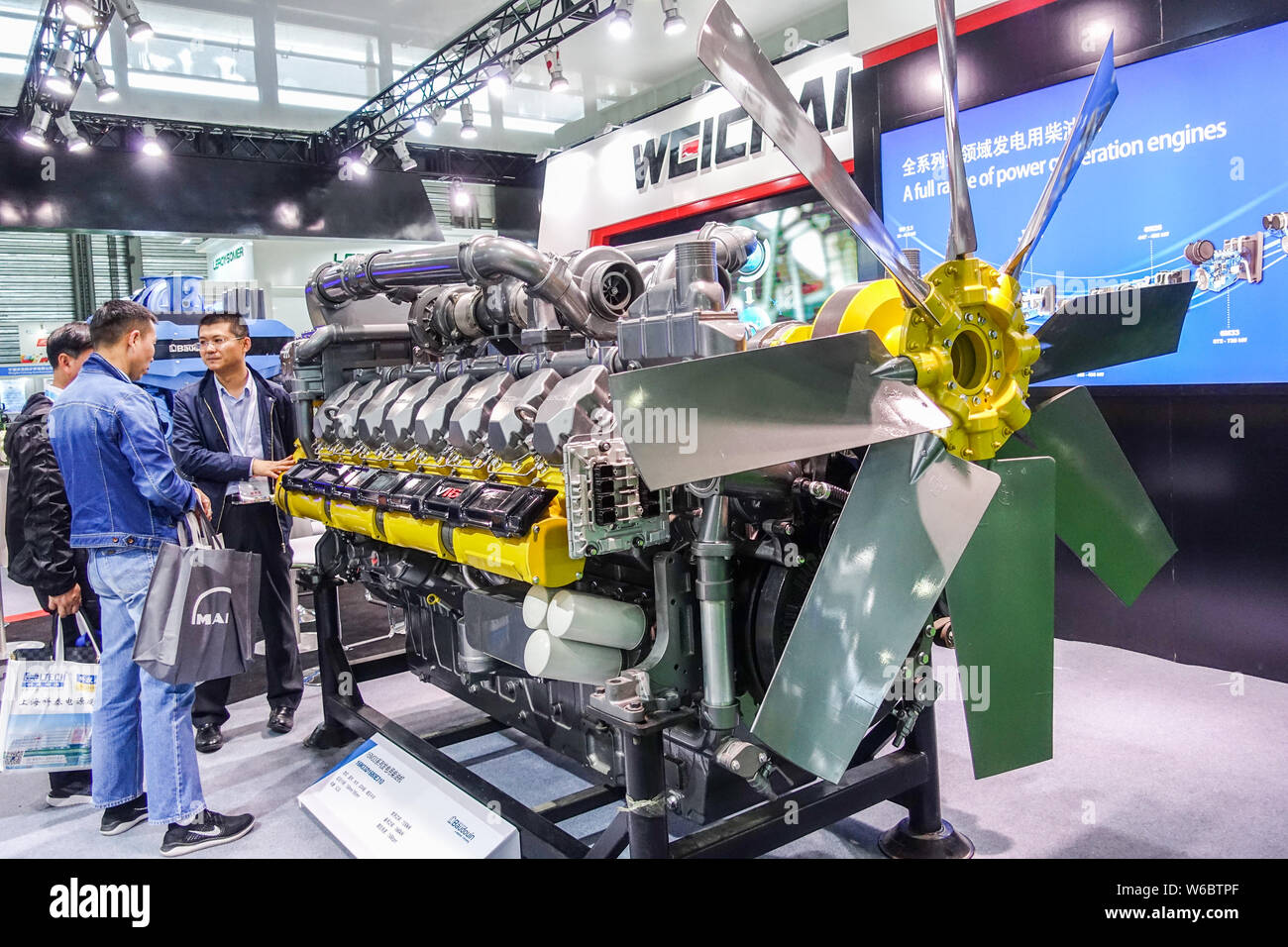 --FILE--Visitors look at a diesel engine at the stand of Weichai Group ...