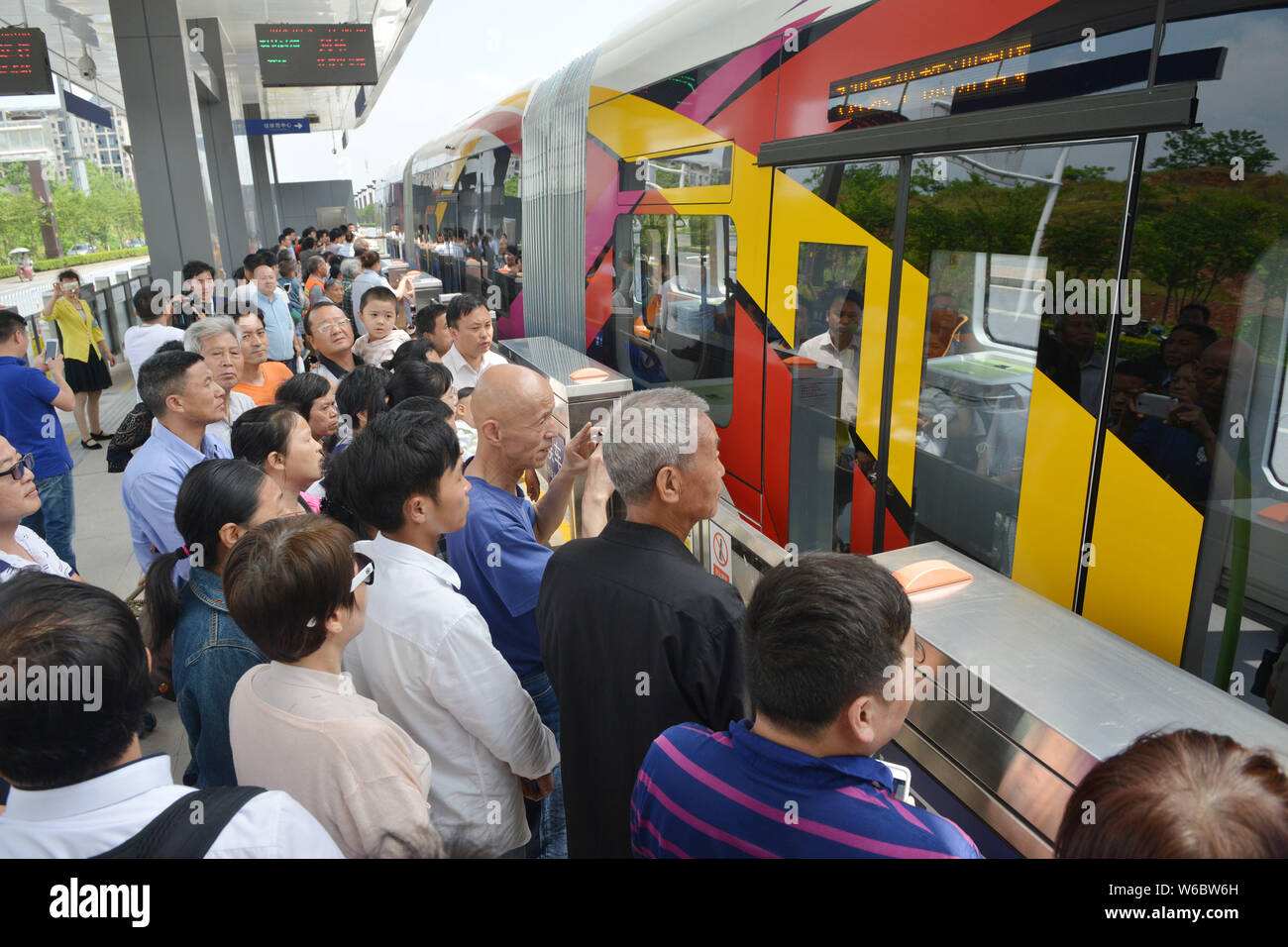 Passengers get on a railless train, developed by the CRRC Zhuzhou ...