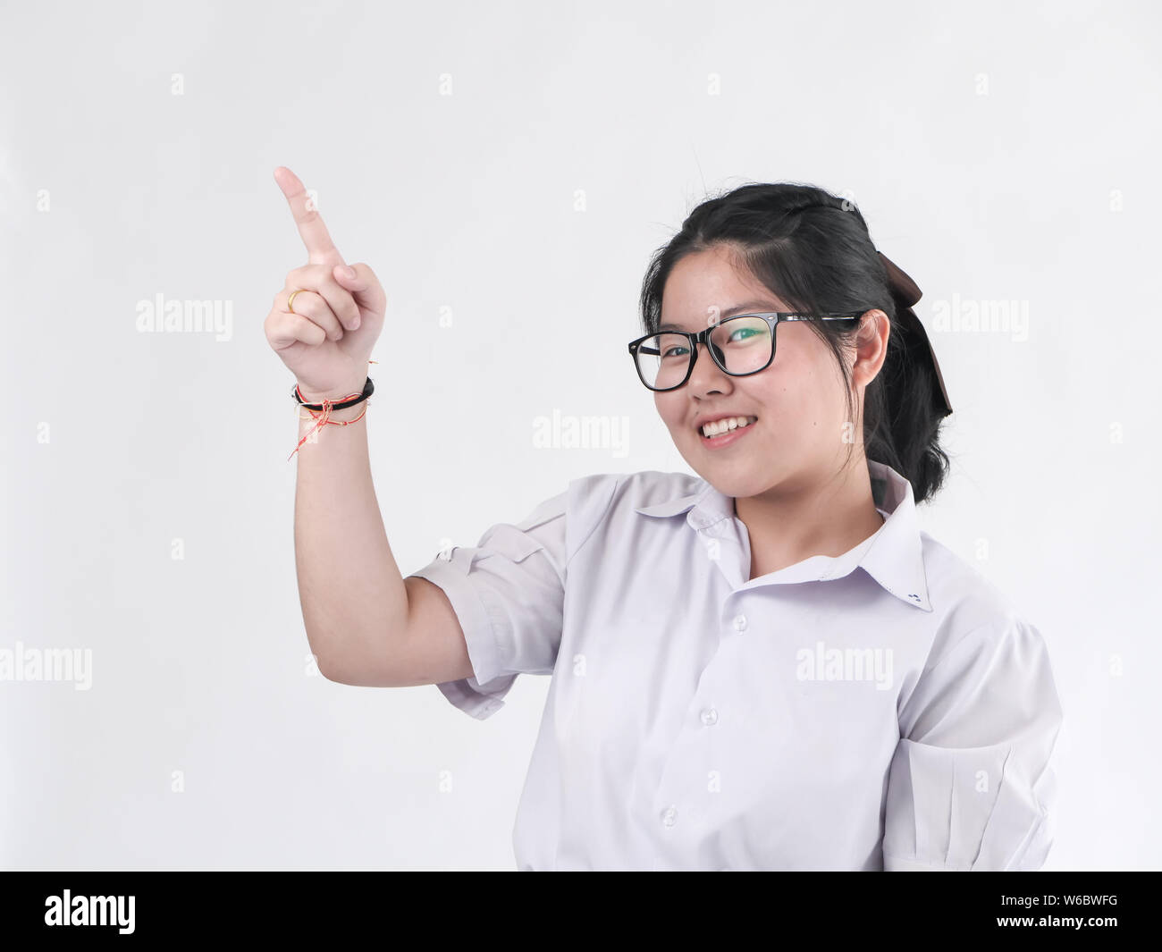 Happy Asian student in uniform pointing something on white background ...