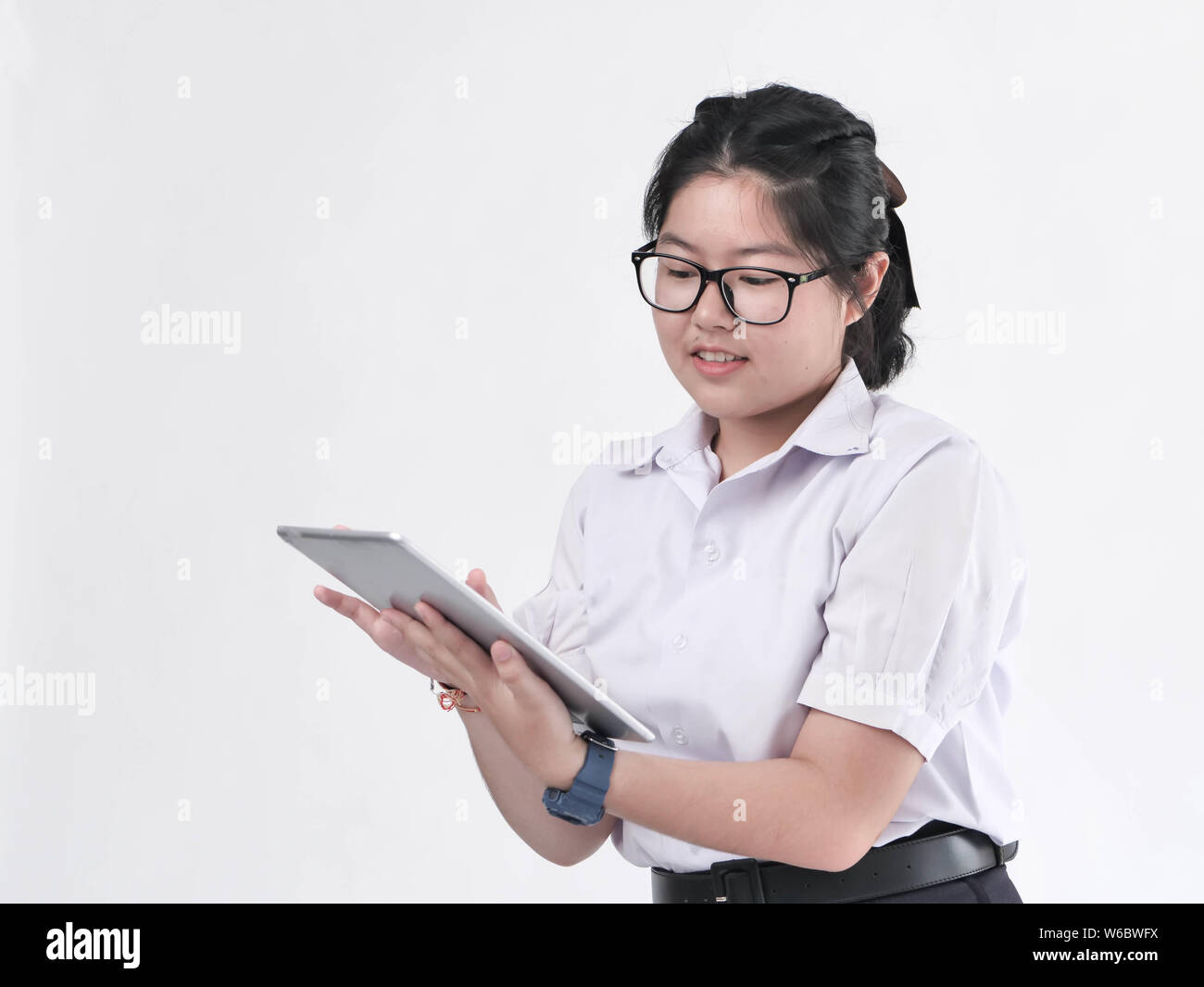 Asian student in uniform using tablet on white background Stock Photo ...