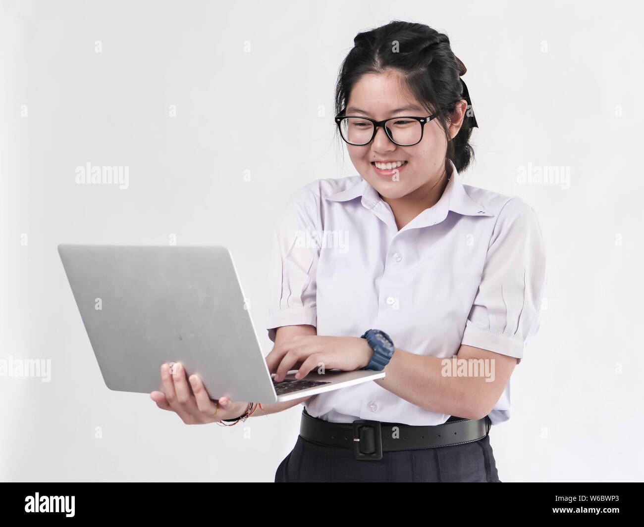 Happy Asian student in uniform using laptop on white background Stock ...