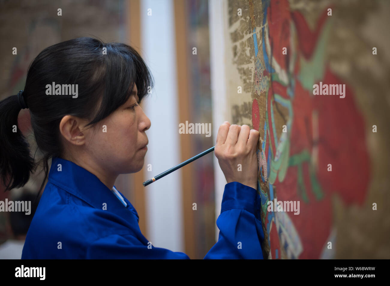 A Chinese worker restores an ancient painting at the Culture Relics ...