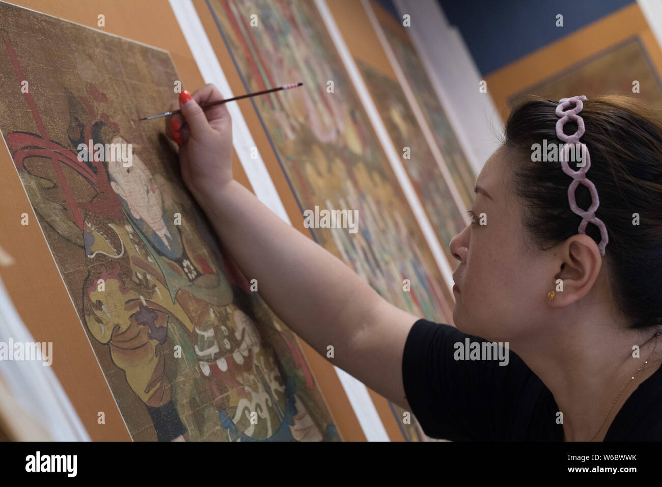 A Chinese worker restores an ancient painting at the Culture Relics ...