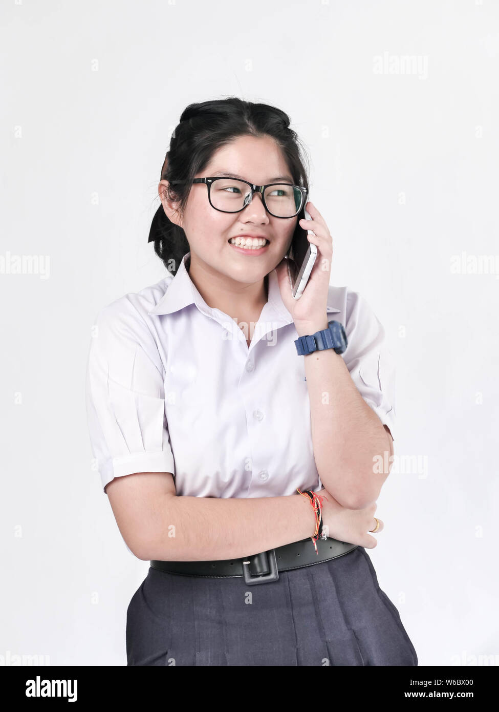 Happy Asian student in Thai uniform using smart phone on white ...