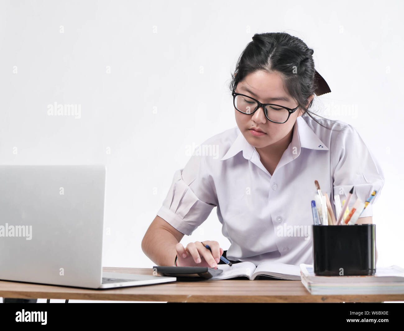 Asian student in Thai uniform doing homework on white background Stock ...