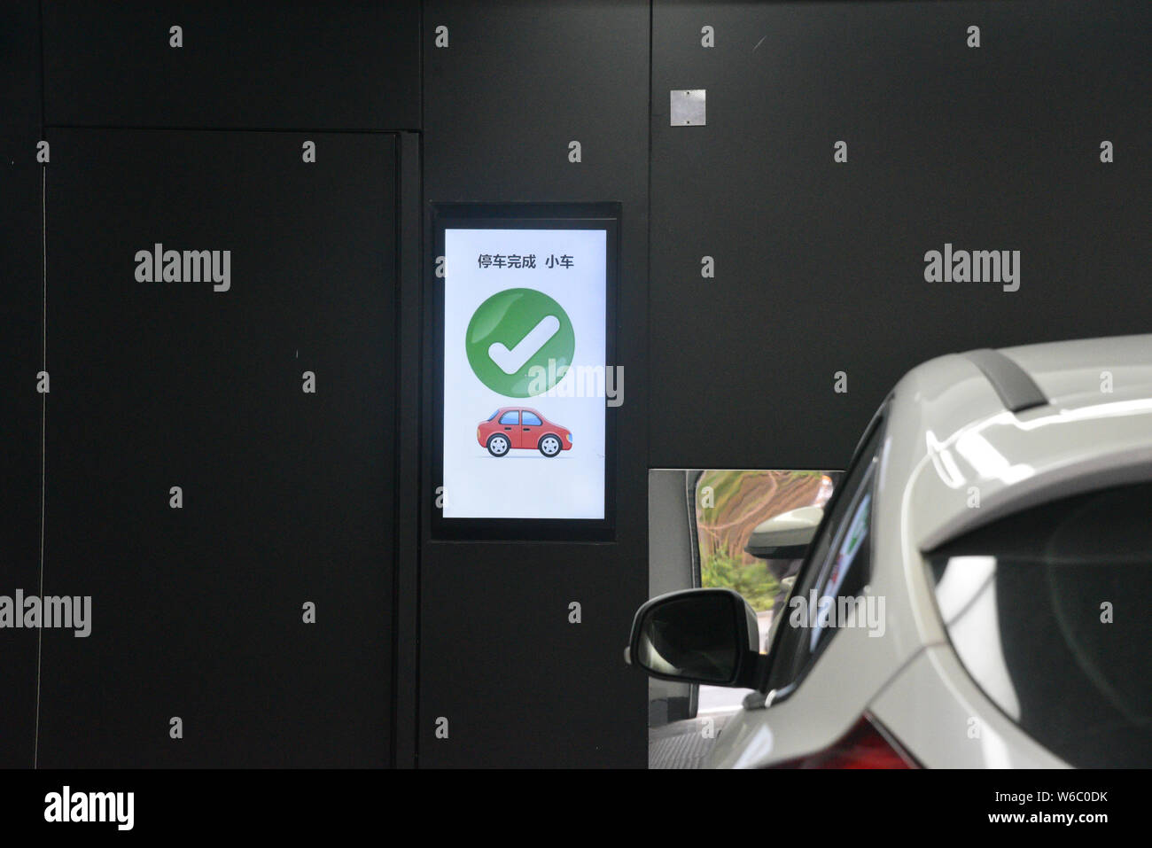 An automated guided vehicle (AGV) robot transfers a car into a parking ...