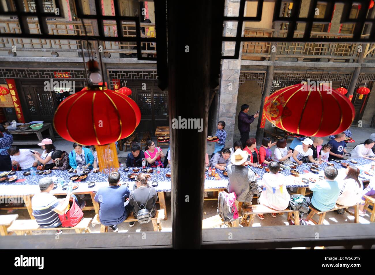 Tourists and local residents eat along tables at along-table banquet ...