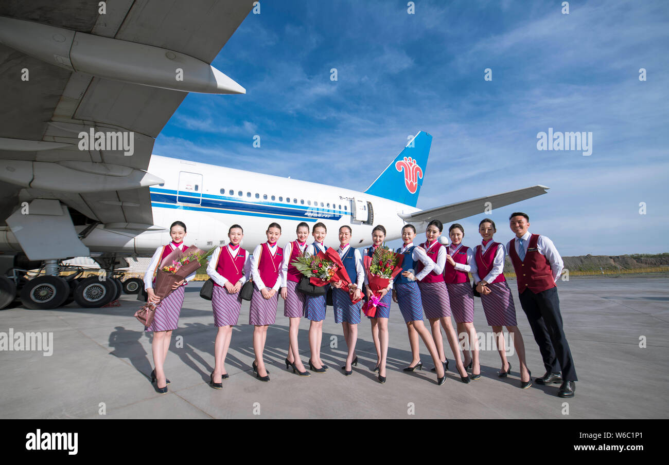 Crew members pose for photos with the Boeing 777-200 jet plane of China ...