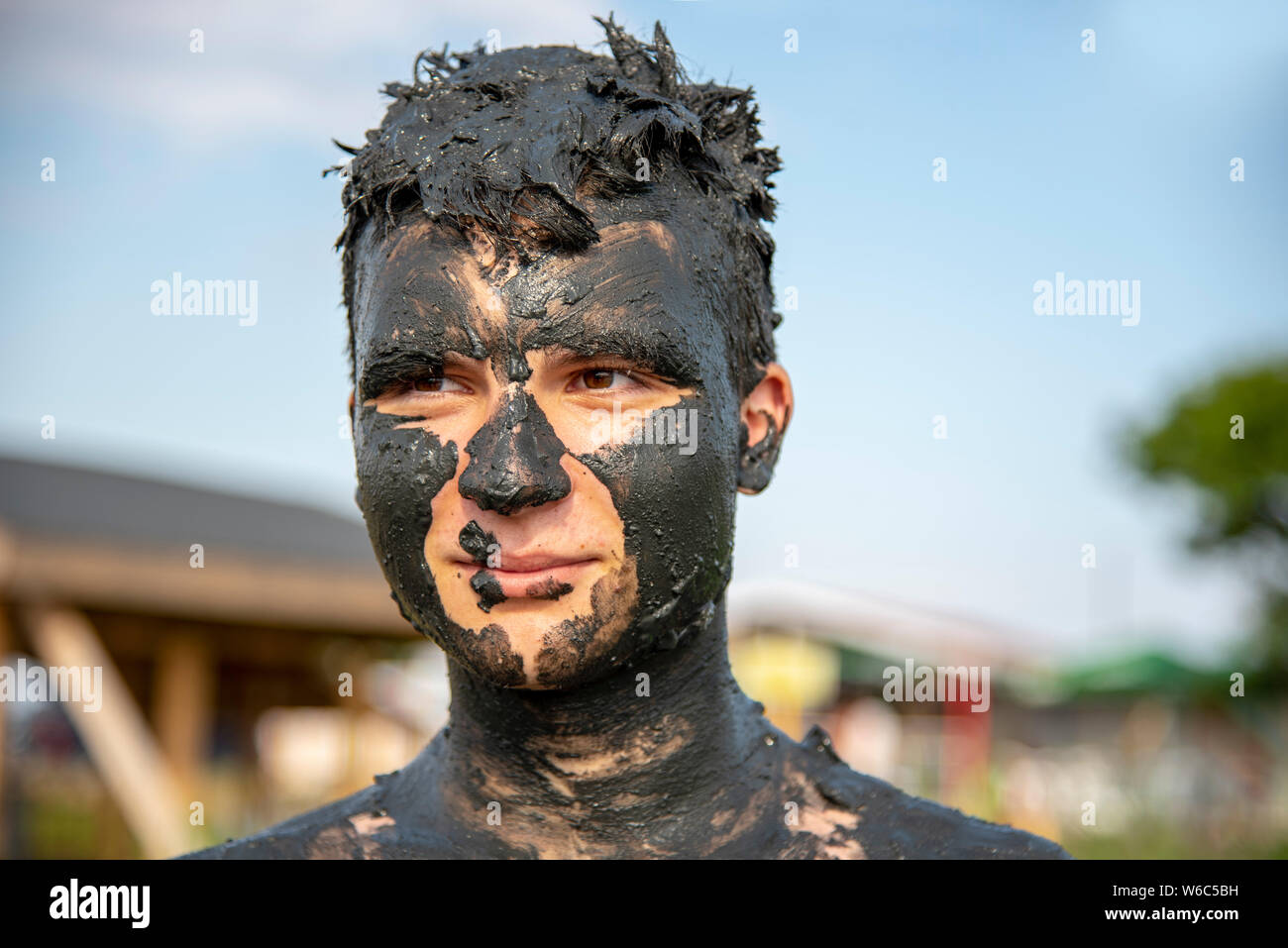 Teenager smeared with mud, visible minor patches of skin Stock Photo ...