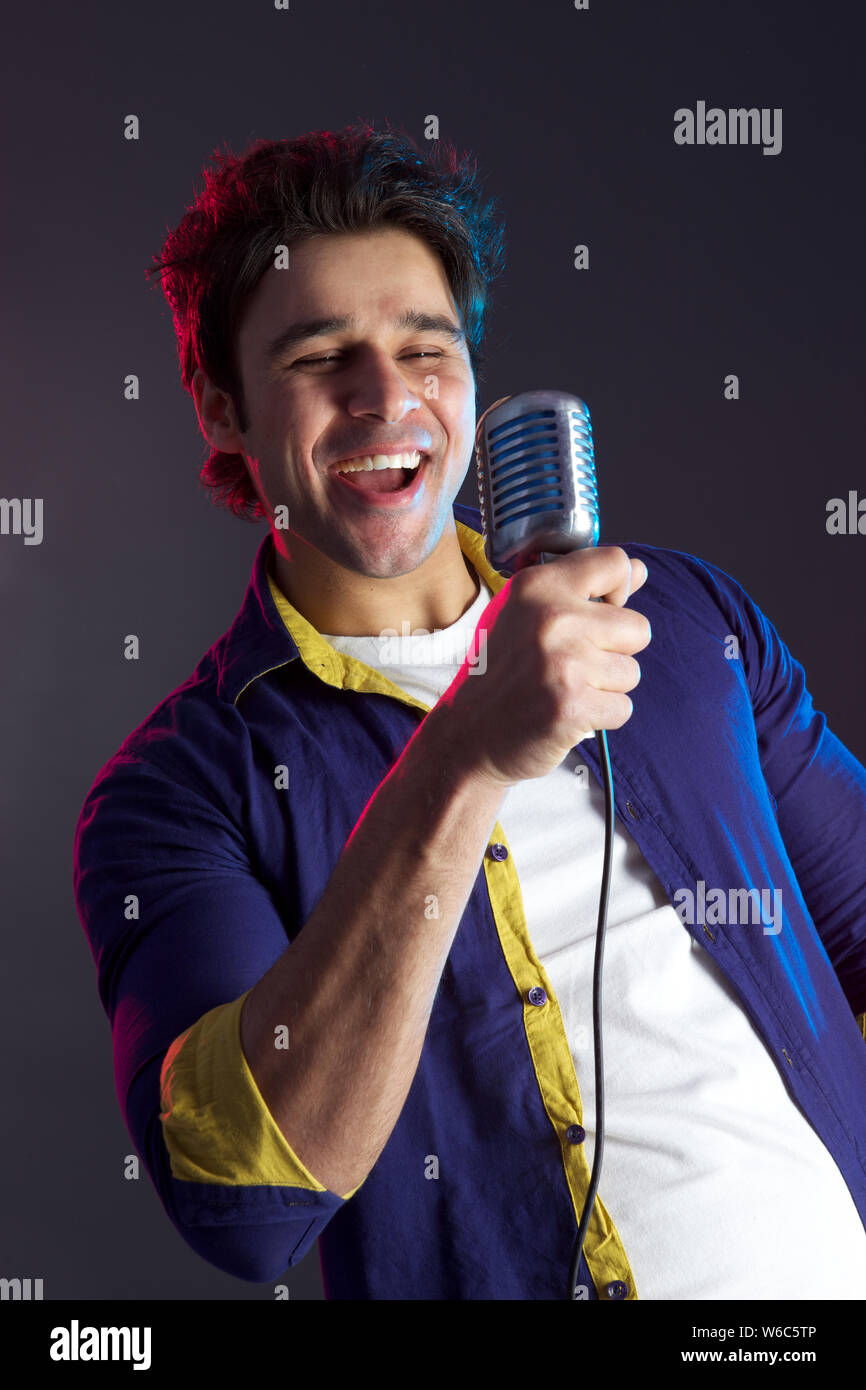 Man singing into microphone and smiling Stock Photo - Alamy
