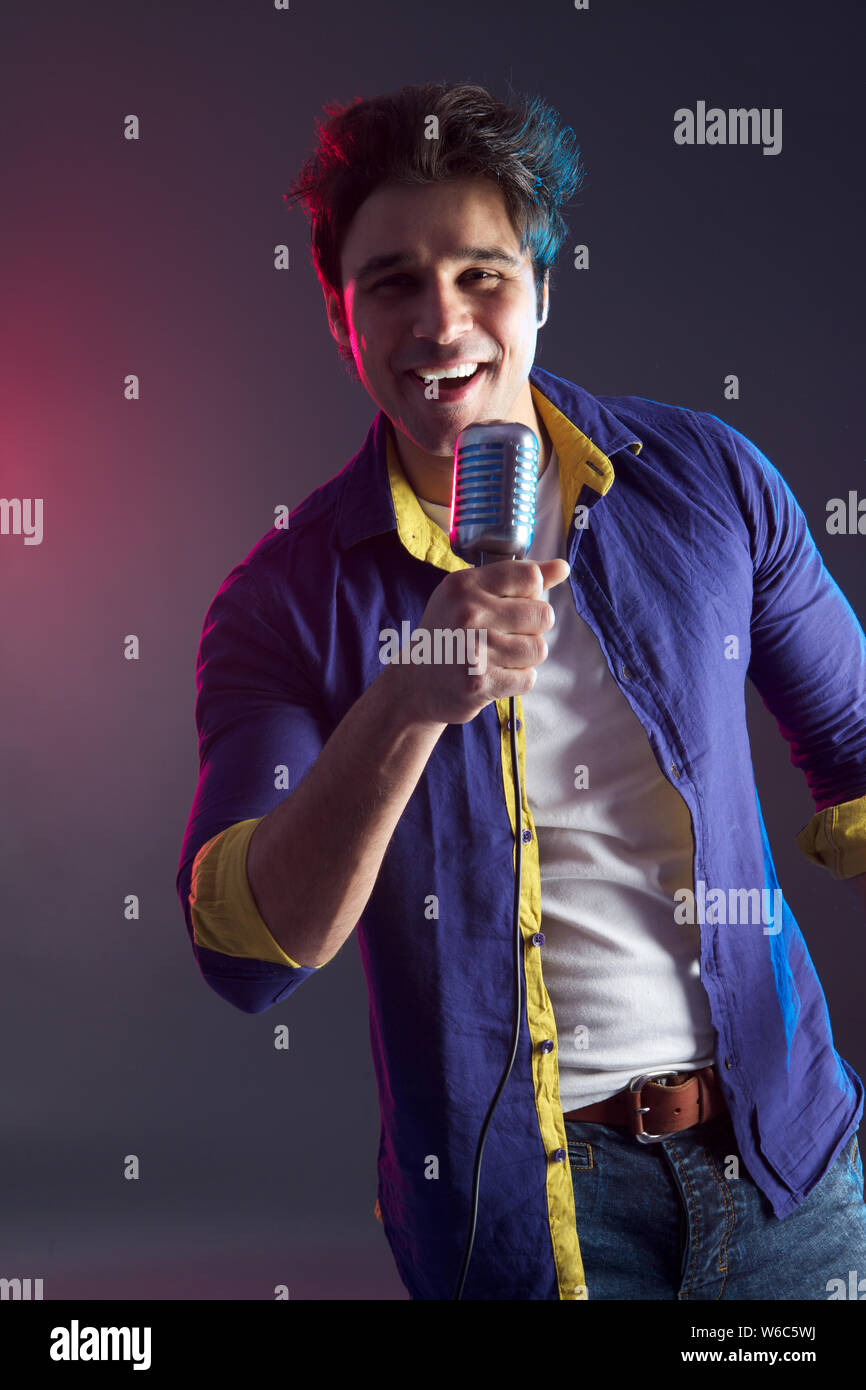 Man singing into microphone and smiling Stock Photo - Alamy