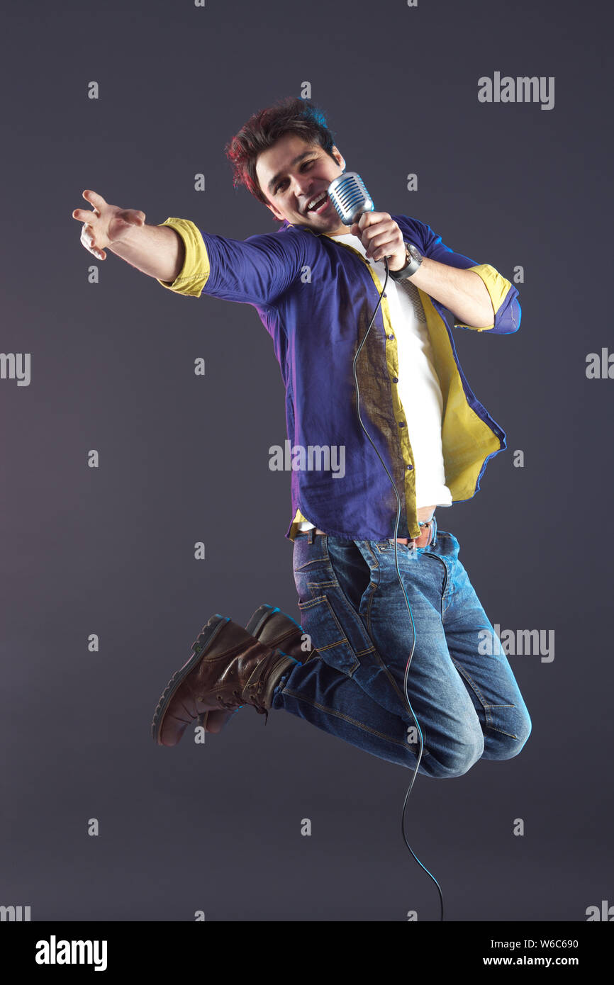 Man jumping in air singing into microphone Stock Photo - Alamy