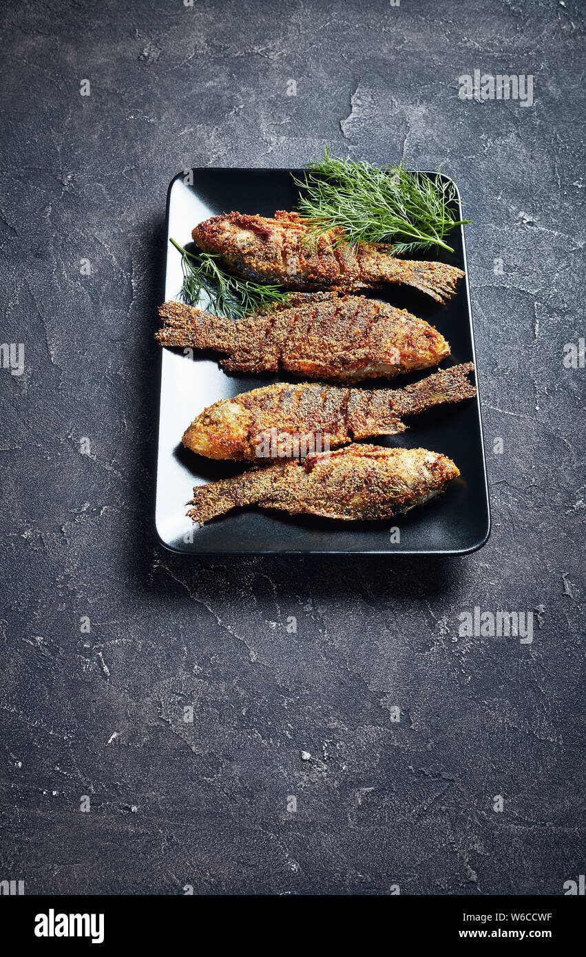 freshly fried crispy crucian carps on a black rectangular plate on a ...