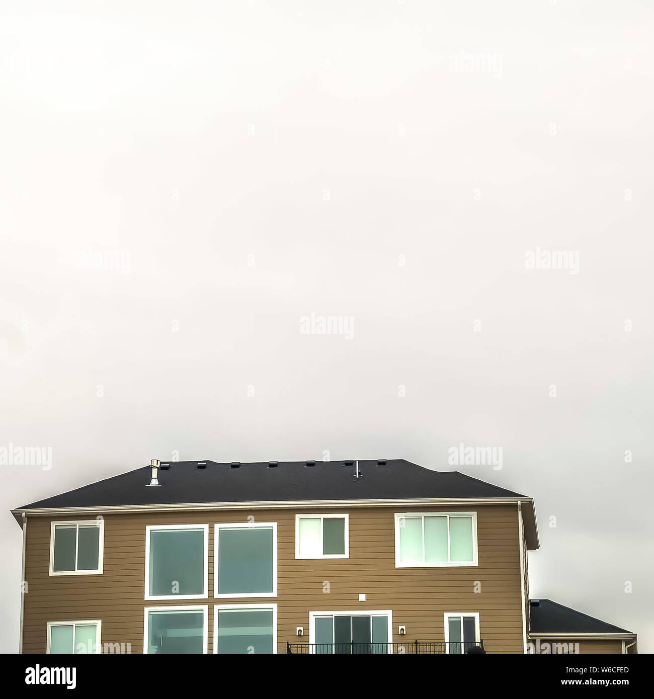 Square frame Bright and cloud filled sky over a residence with brown ...