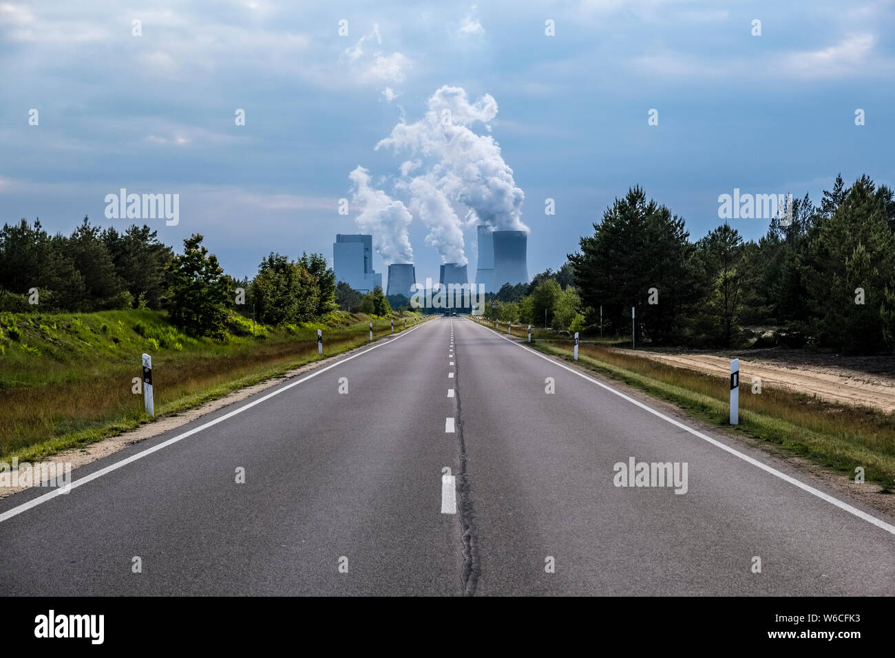 The steaming cooling towers of a coal-fired power plant behind a ...