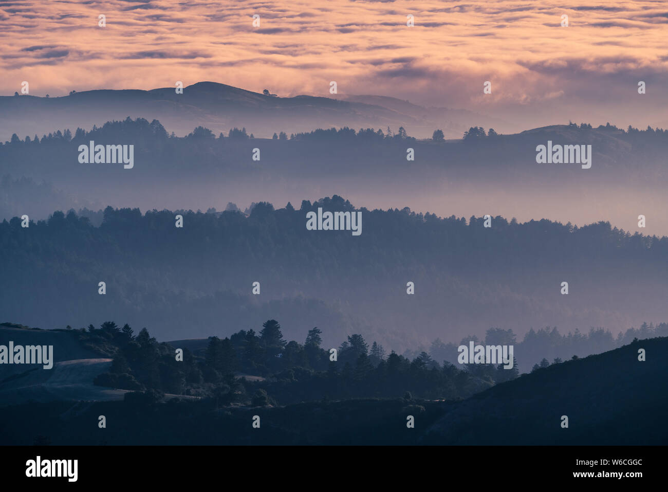 Sunset view of layered hills and valleys covered by a sea of clouds in ...