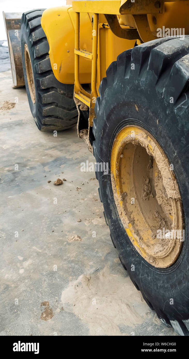 Vertical frame Close up view of the black rubber wheel of a yellow ...