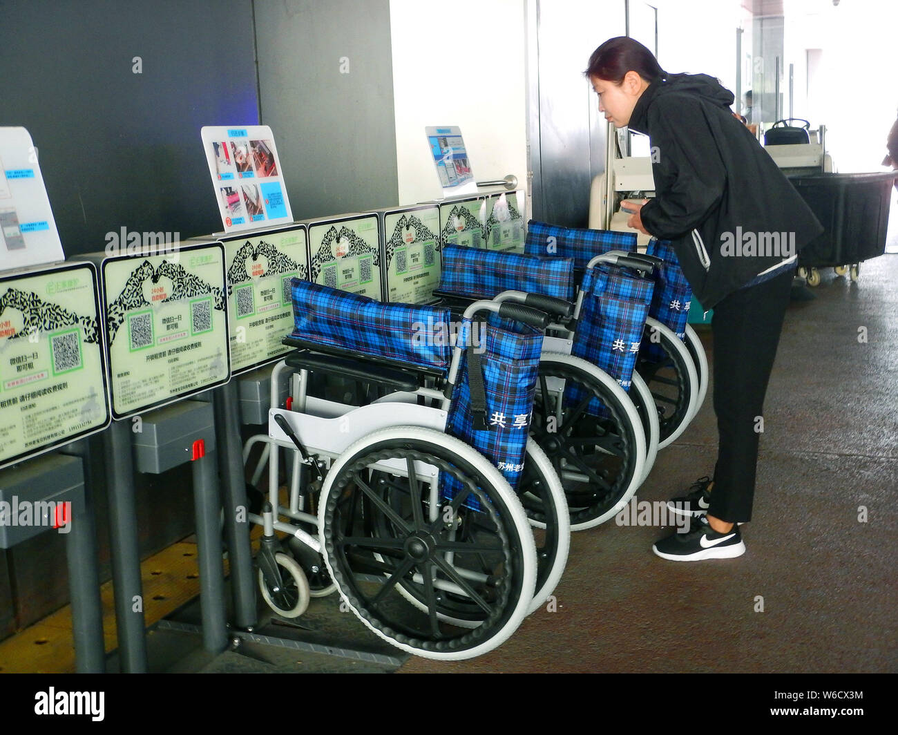 A woman scans the QR code next to a shared wheelchair to rent it for a ...