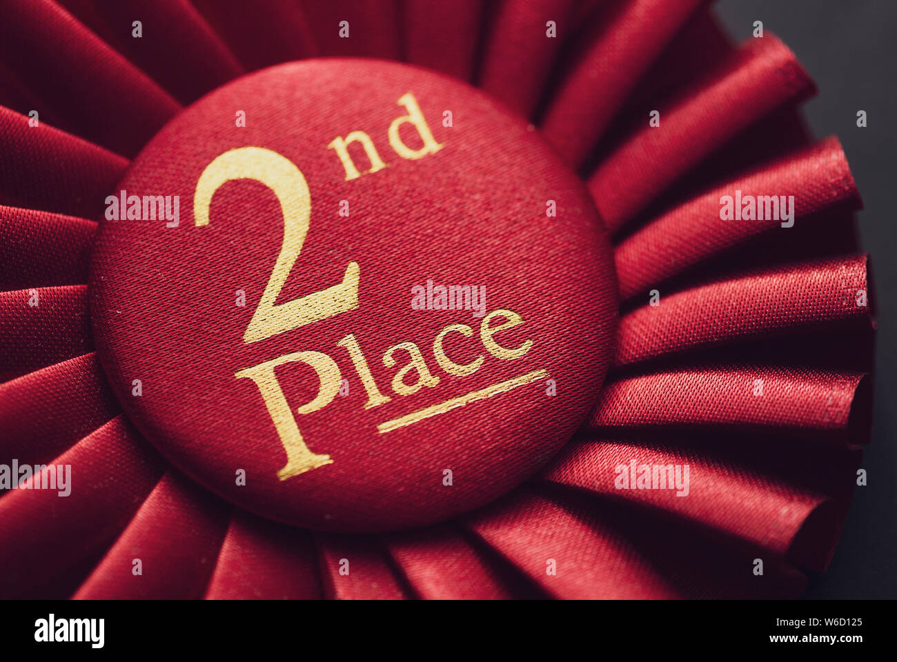 Closeup winner 2nd place red rosette with gold text on black background ...