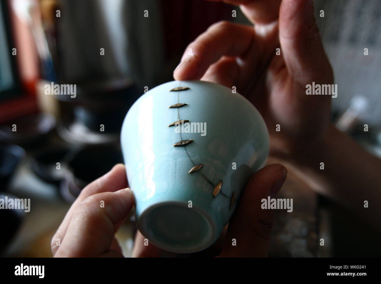 Chinese craftsman Xiong Haoyang shows a ceramic after repairing broken ...