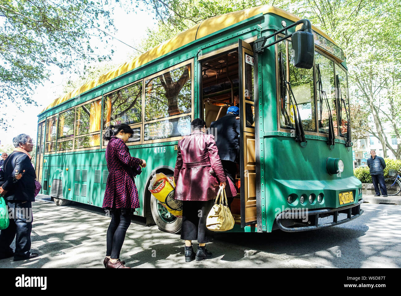 Passengers get on a trolley-shaped bus, locally known as a dangdangche ...