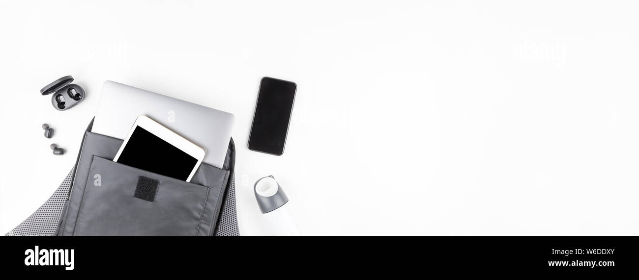 Creative top view flat lay of open backpack with laptop and tablet ...