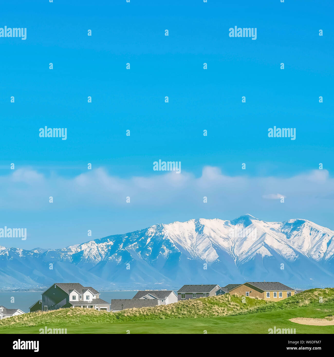 Residential area overlooking a lake and snow peaked mountain under blue ...