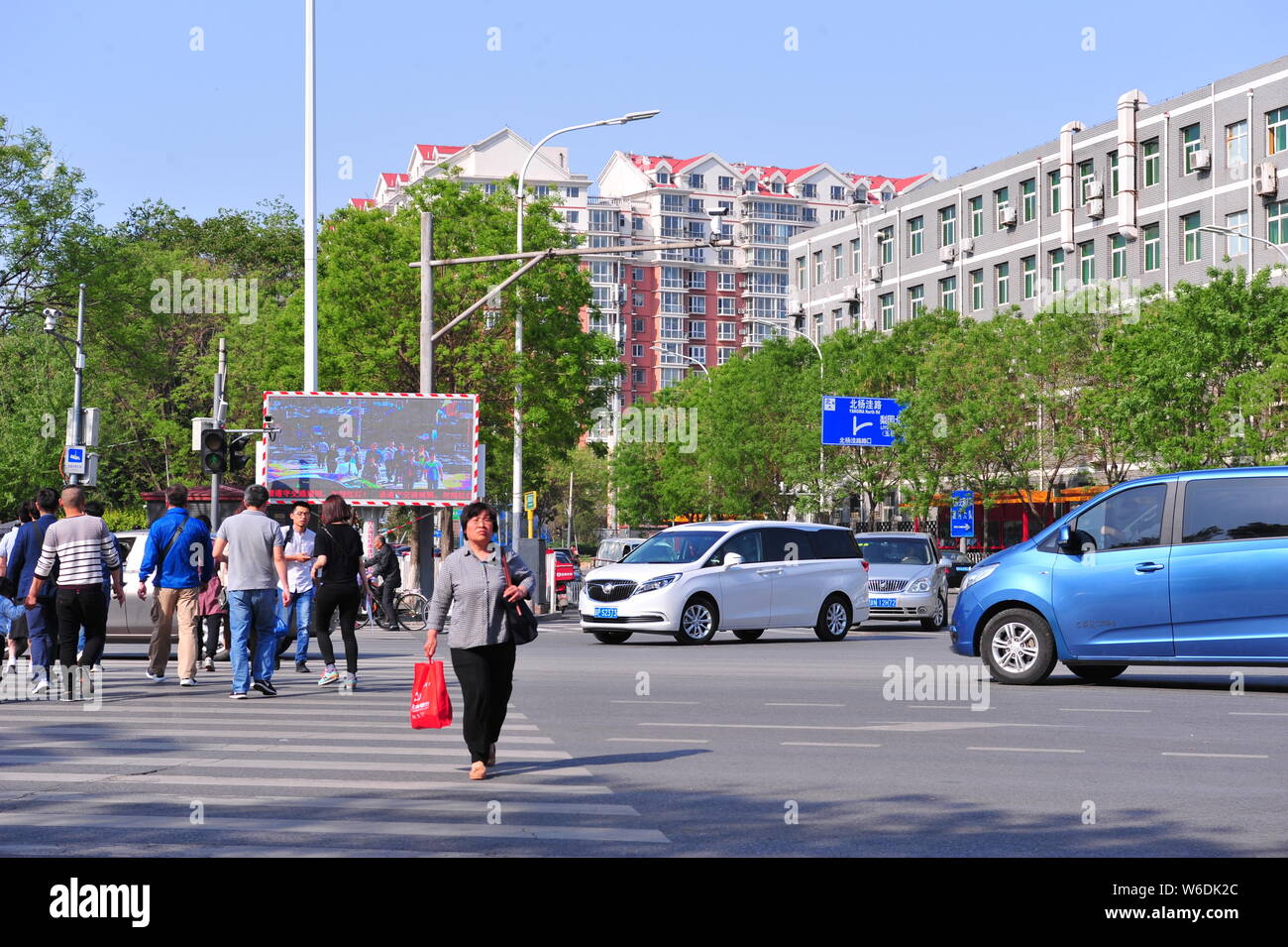 Pedestrians walk on a zebra crossing as the red light turns green in ...