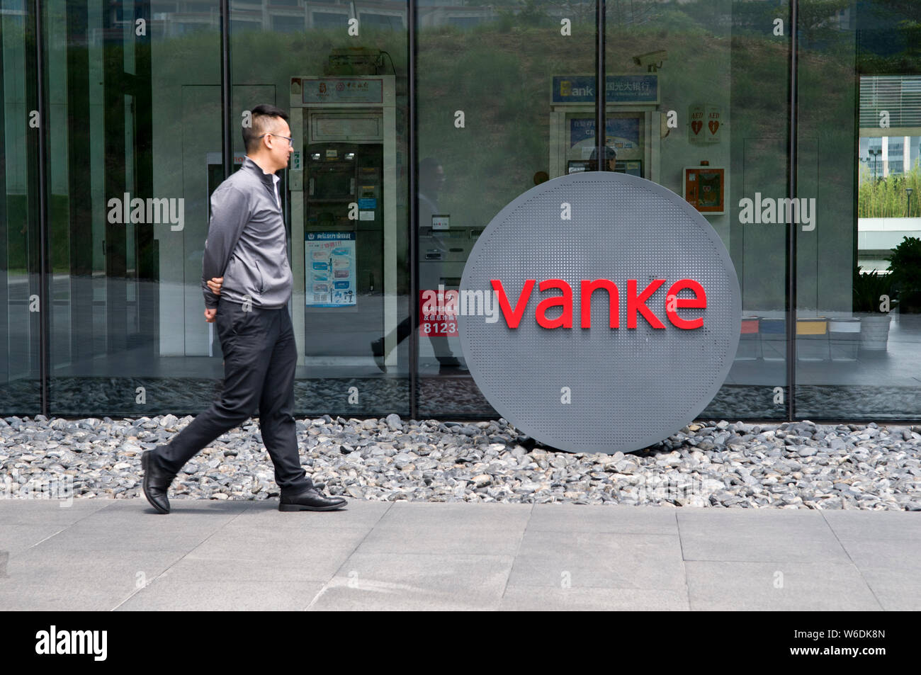 --FILE--A pedestrian walks past a logo of Vanke in Shenzhen city, south ...