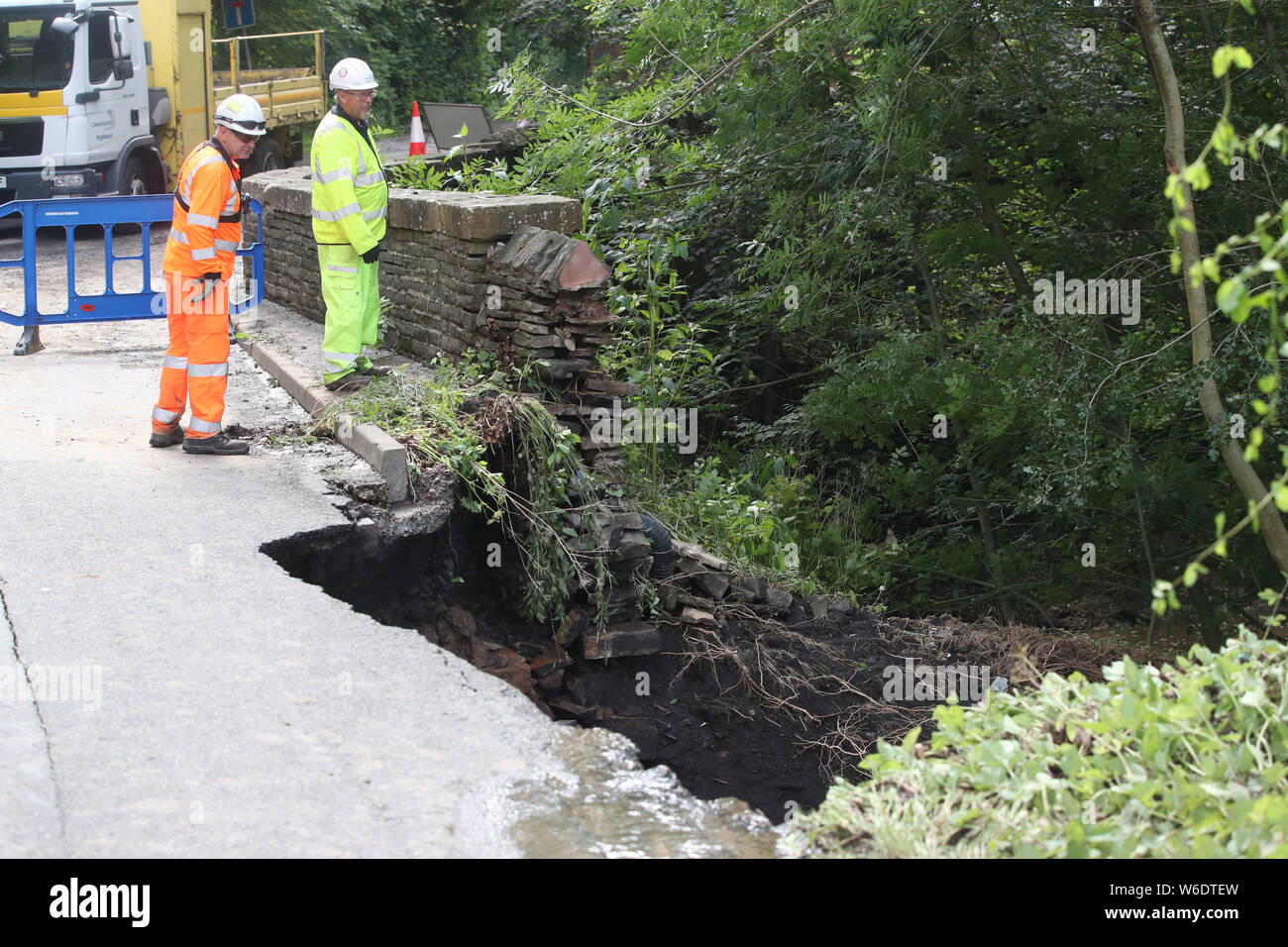 Workers look at a partially collapsed bridge in Poynton, Cheshire ...