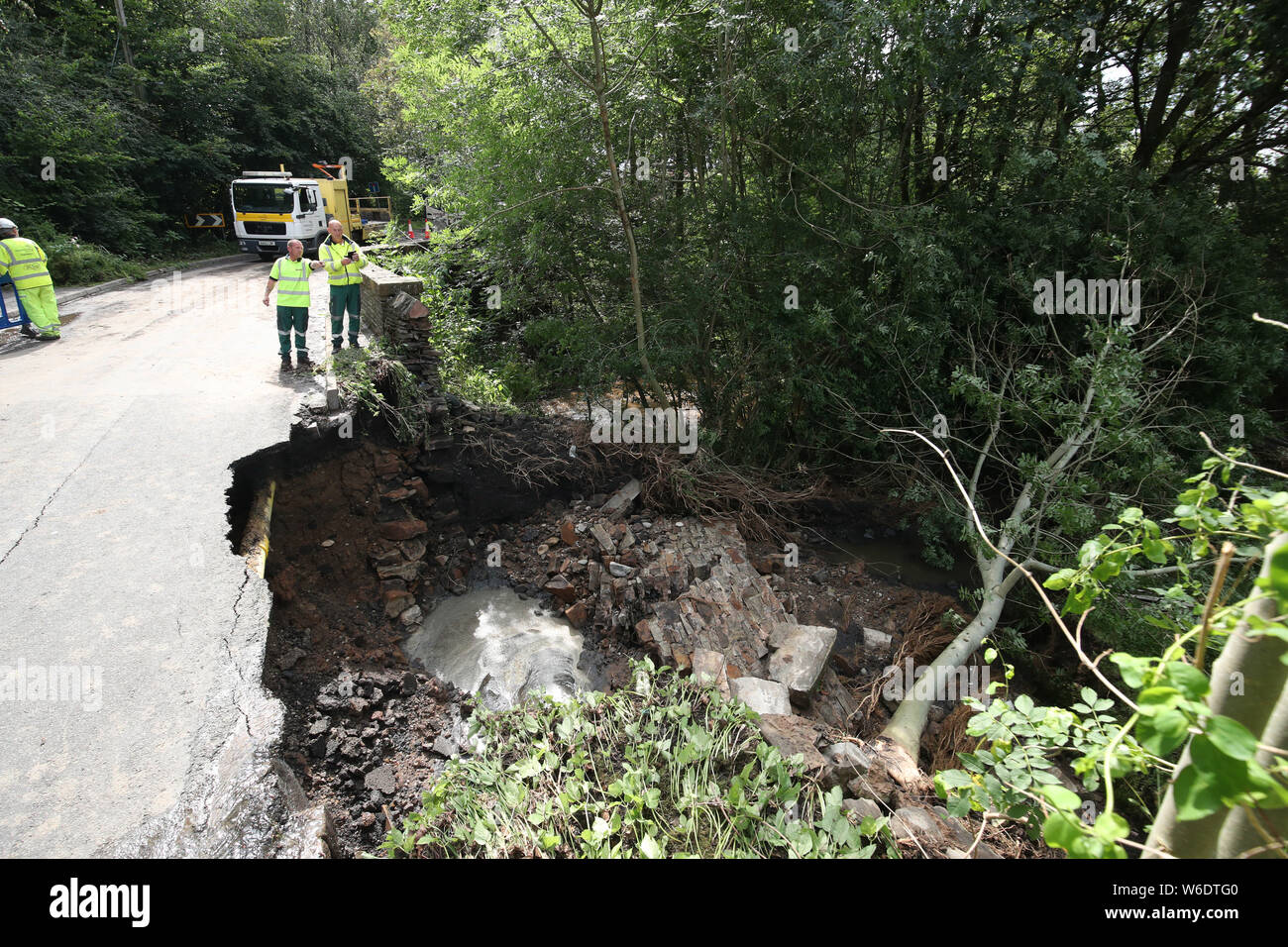 Workers look at a partially collapsed bridge in Poynton, Cheshire ...