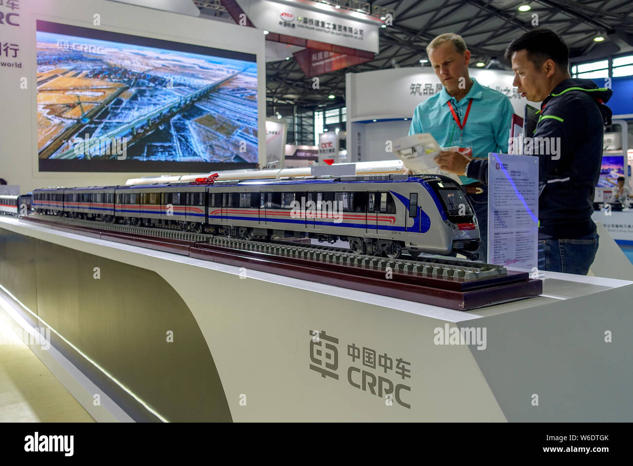 Visitors look at a model train on display at the stand of CRRC (China ...