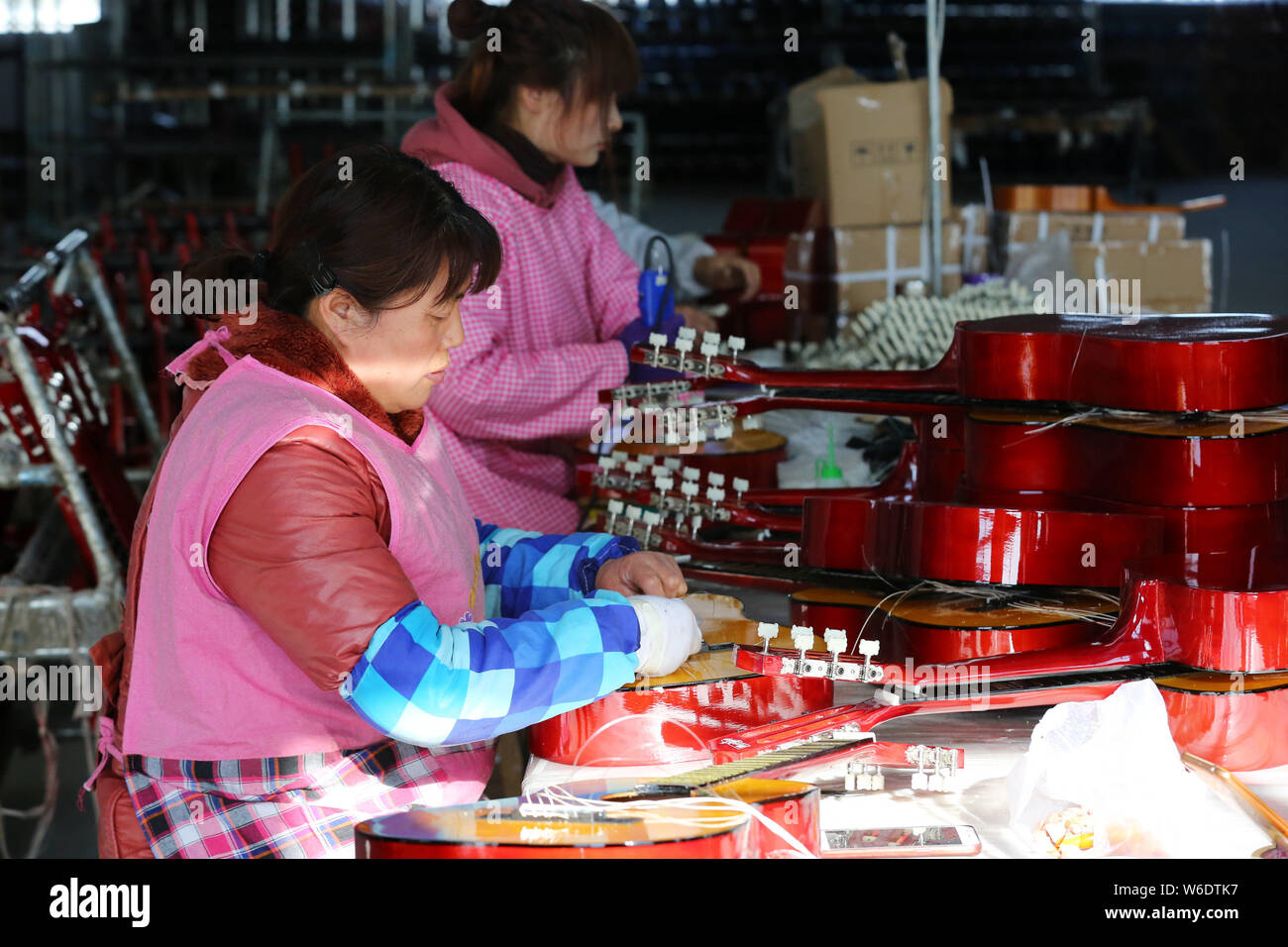 Chinese workers manufacture wooden guitars at a factory in Sangxu town ...