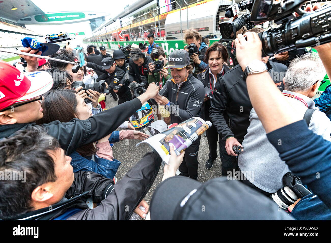 Spanish F1 driver Fernando Alonso of McLaren autographs for fans at the ...